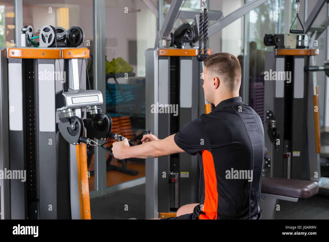 Handsome young fit man training on row machine in gym room in fitness ...