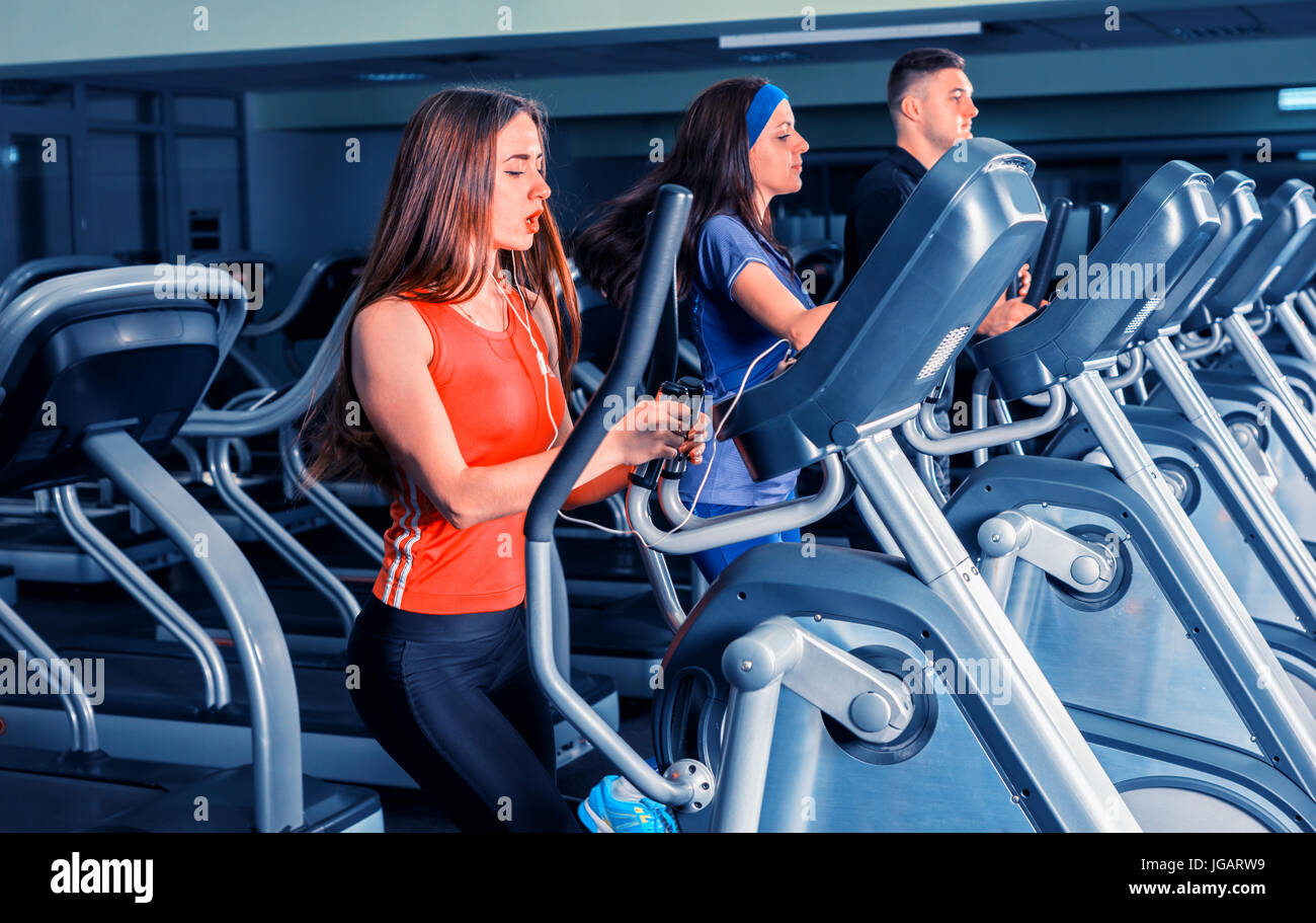 Young people diligently exercising on the crosstrainer machines in ...