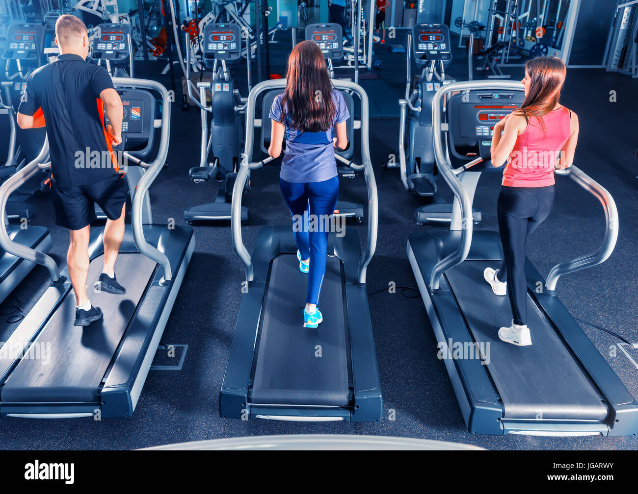 Rear view of group of fit friends exercising on a treadmill at the ...