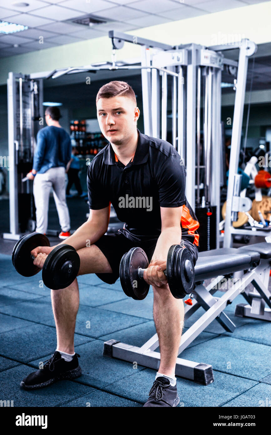 Handsome young sportive man in sportswear lifting some weights and ...