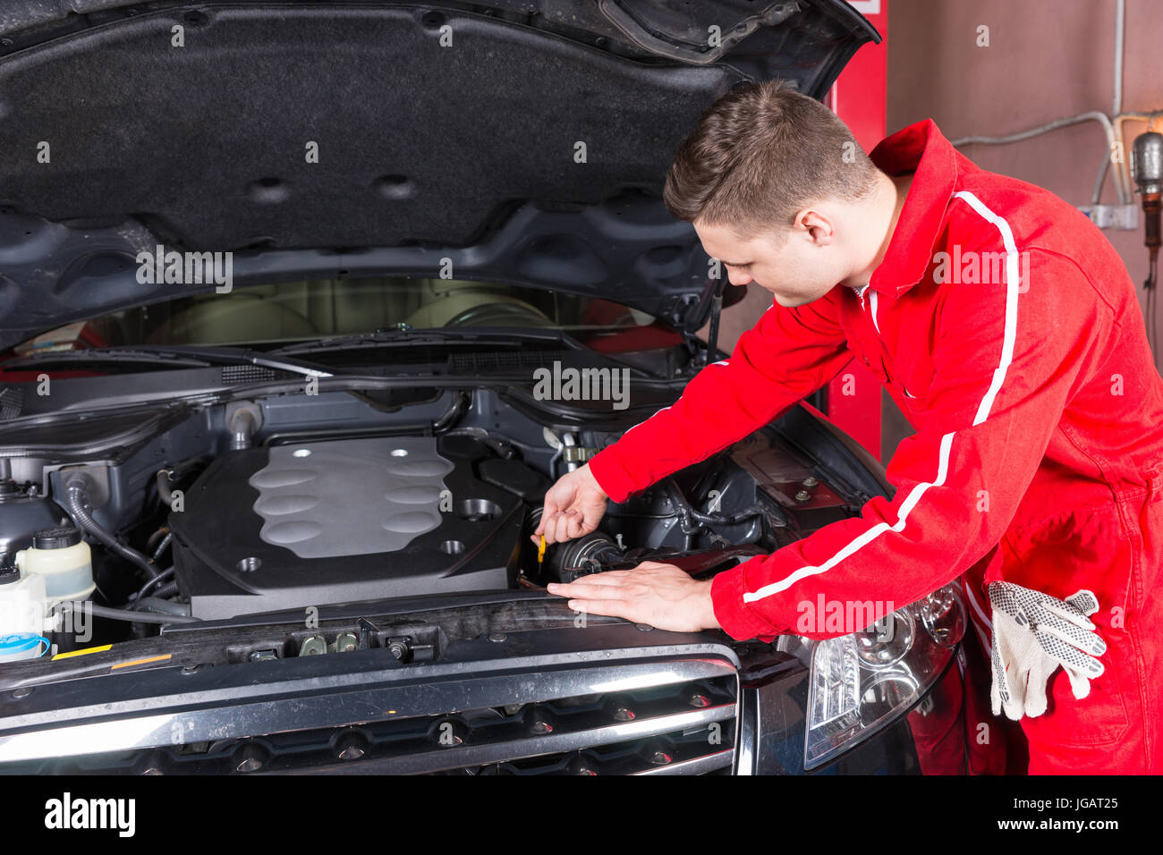 Male motor mechanic is going to check the oil level in a car engine ...