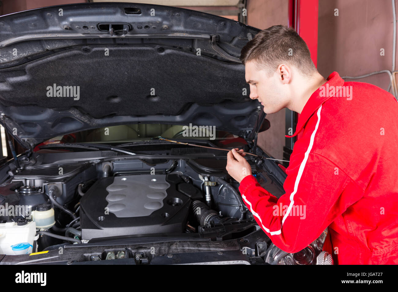 Motor mechanic checking the oil level in a car engine holding the ...