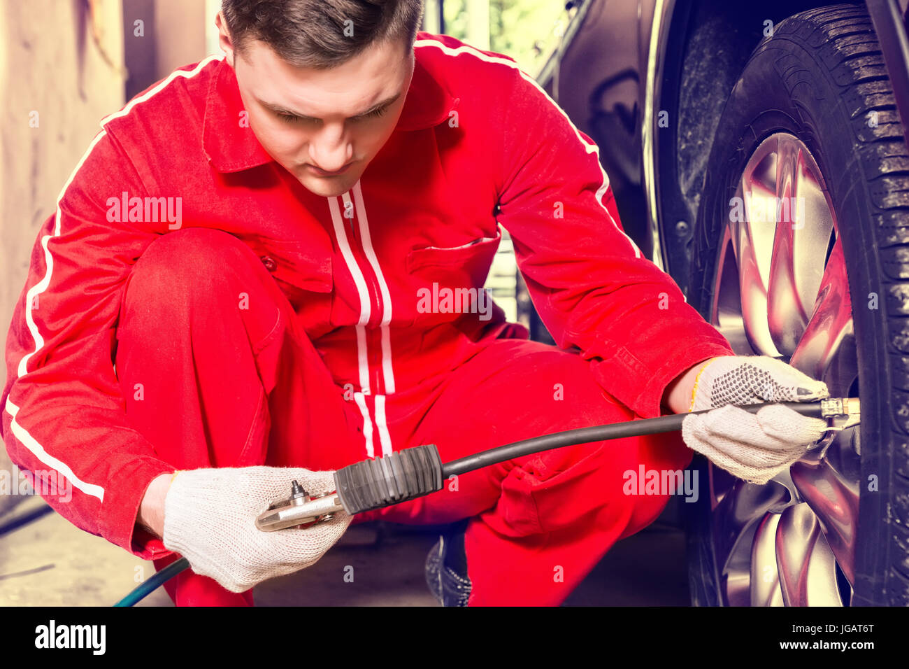 Concentrated motor mechanic checking the air pressure of a tyre ...