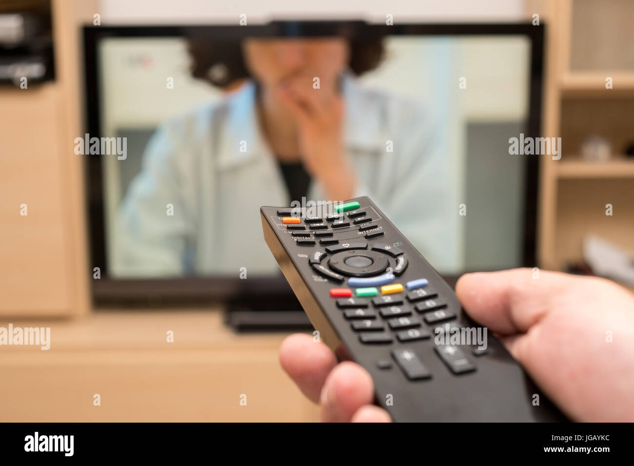 Watching TV and holding black modern remote controller. Shallow dof ...