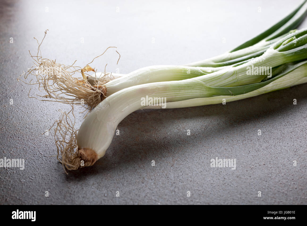 Fresh green onion stalks with water drops on ceramic hob background ...
