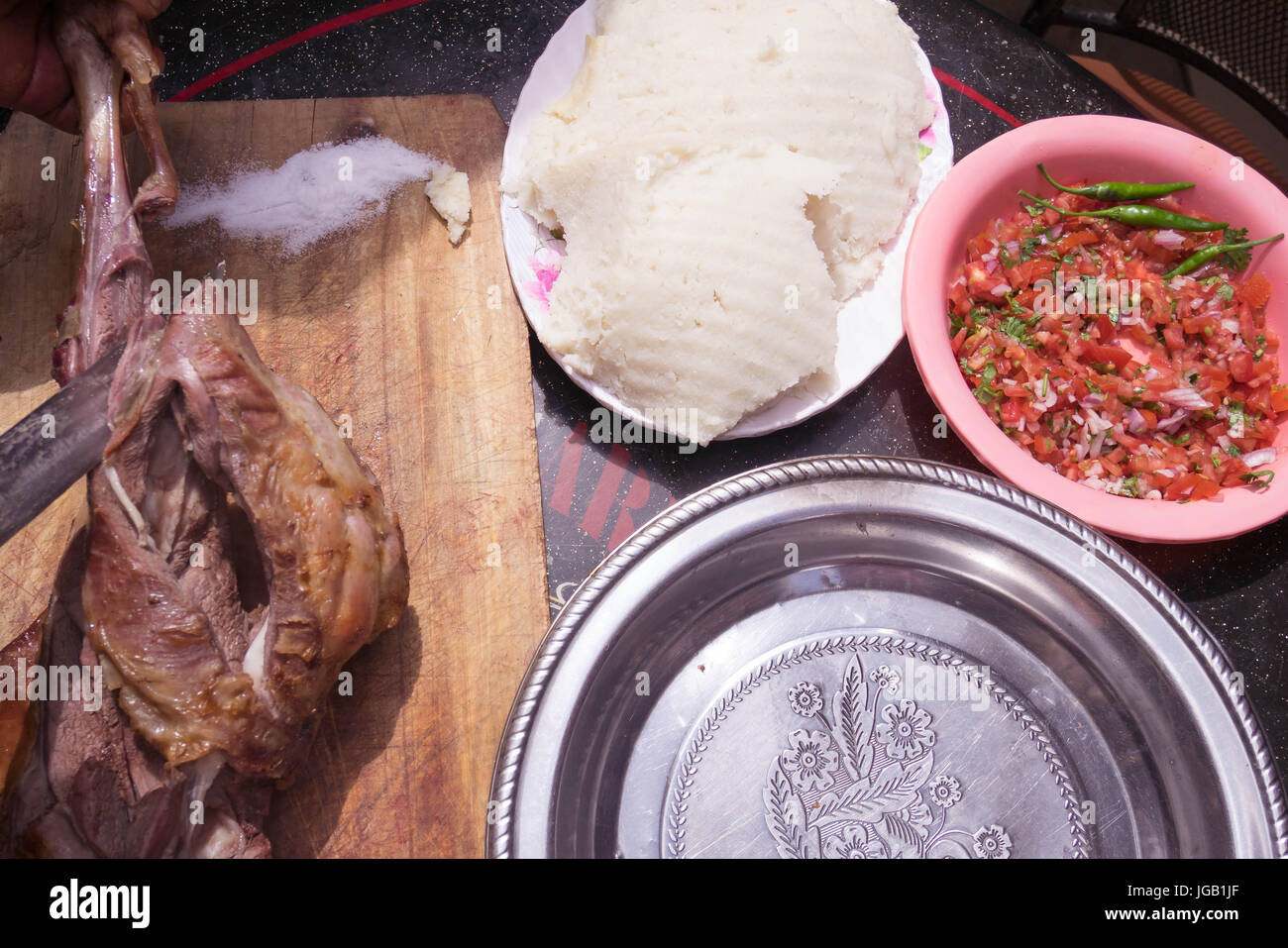 Grilled lamb meat with tomato salad and ugali Stock Photo - Alamy