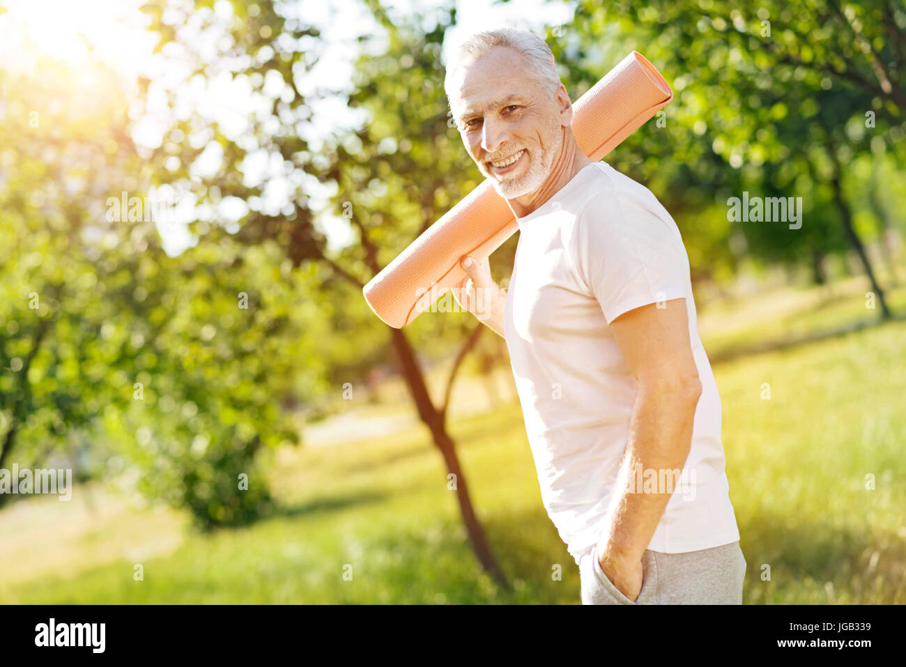 Cheerful aged man holding roll mat on the shoulder Stock Photo - Alamy