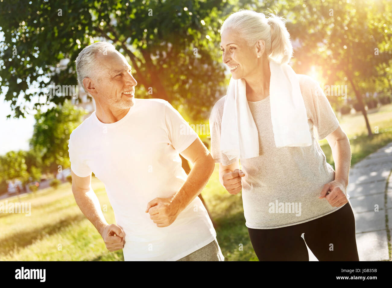 Cheerful retired smiling couple jogging together Stock Photo - Alamy