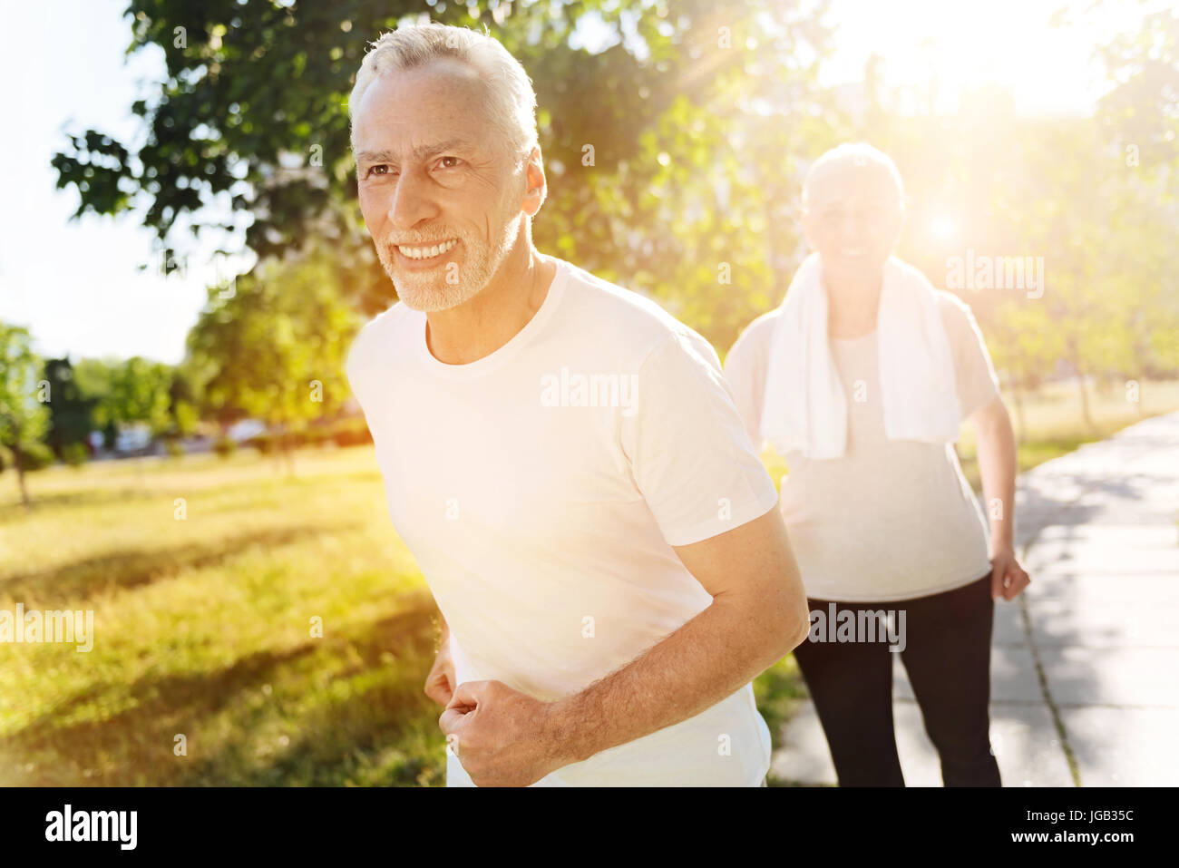Cheerful retired man jogging with his wife Stock Photo - Alamy