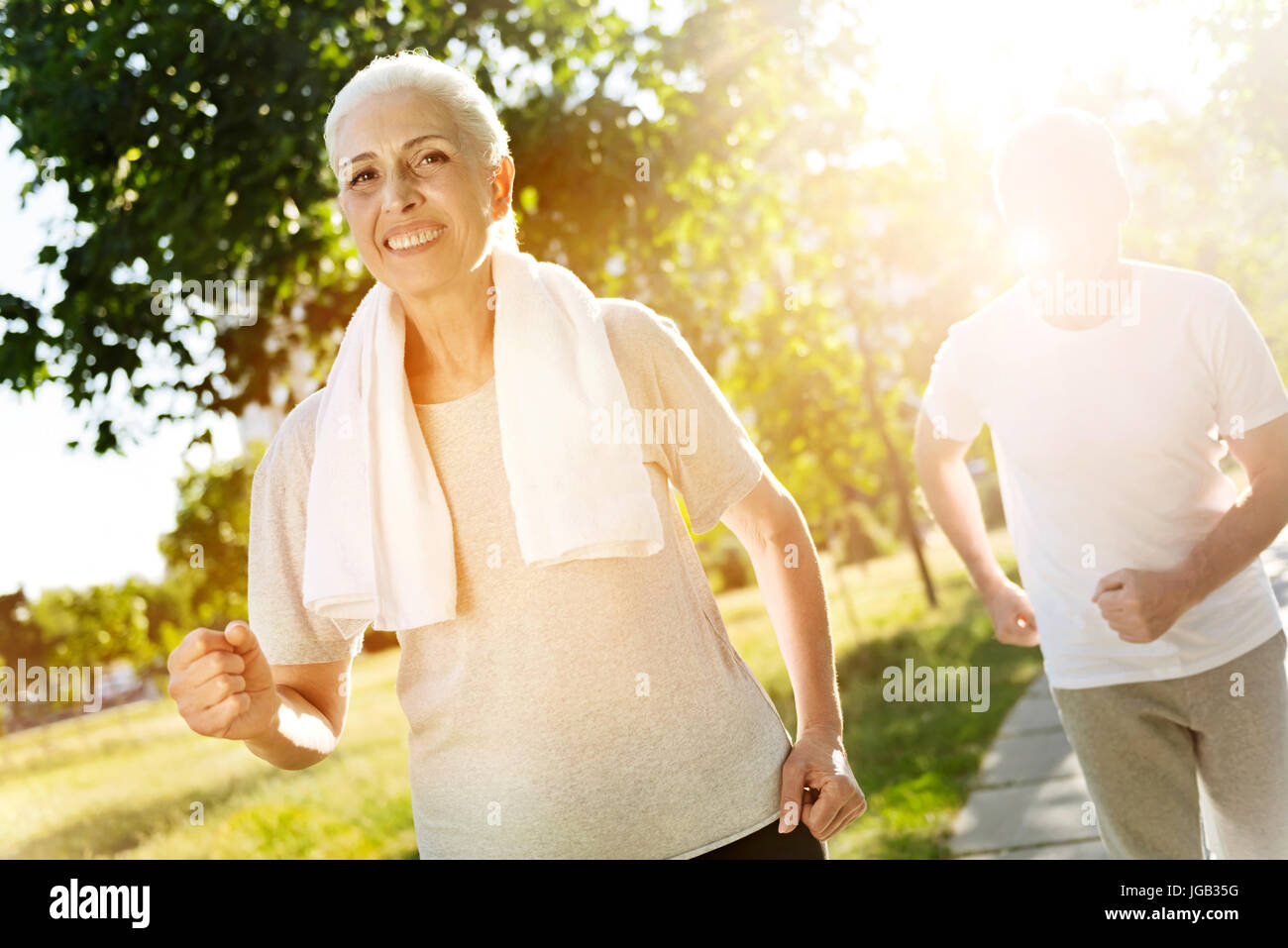 Positive senior woman jogging with her husband Stock Photo - Alamy