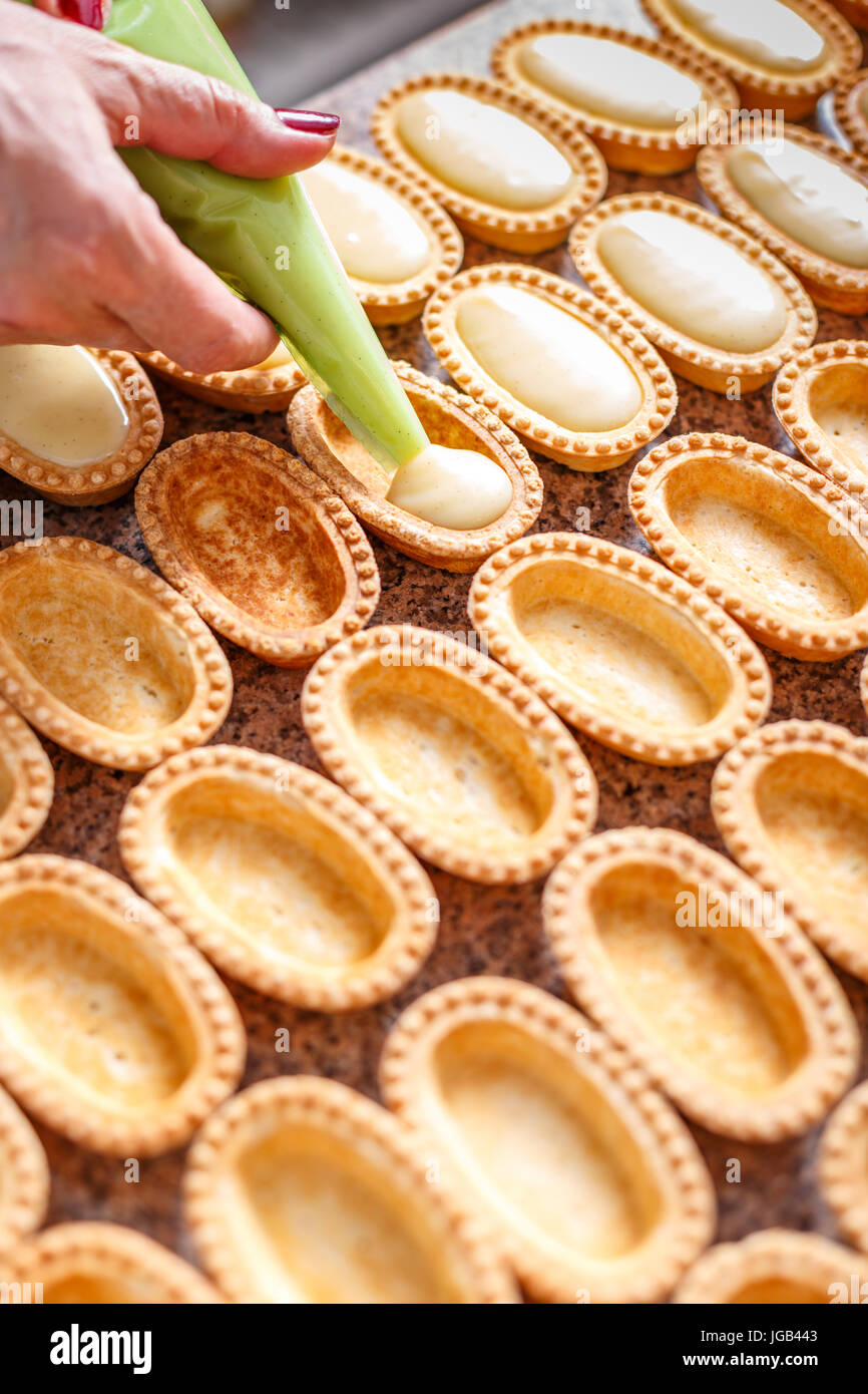 Preparing small pastry tartlets filled with vanilla cream Stock Photo ...