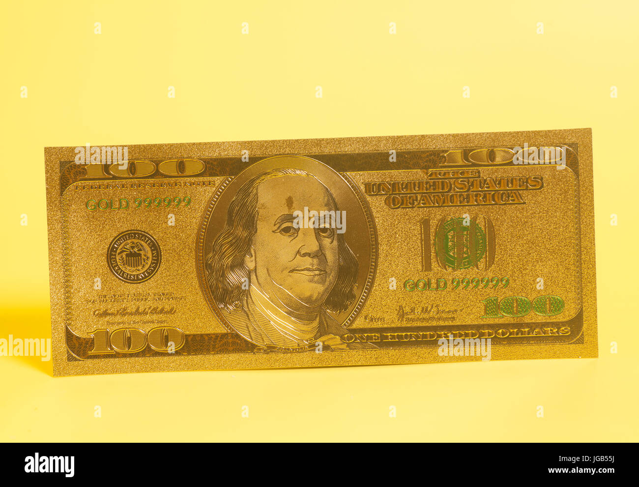 Golden one hundred U.S dollar bill on yellow background Stock Photo - Alamy