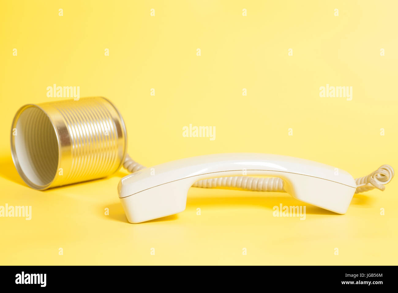 Tin can phone with handset on yellow background Stock Photo - Alamy