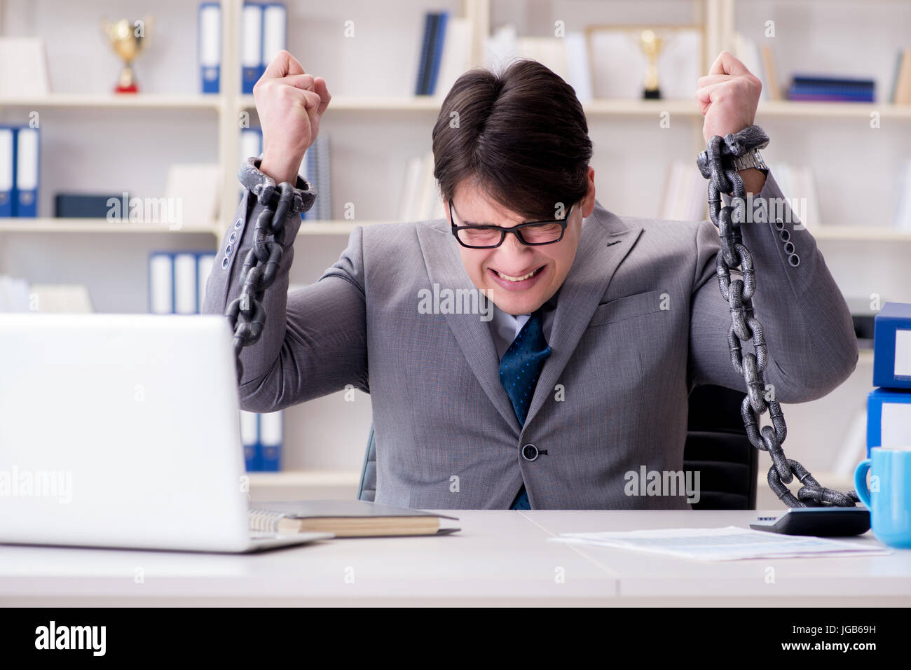 Businessman tied with chains to his work Stock Photo - Alamy