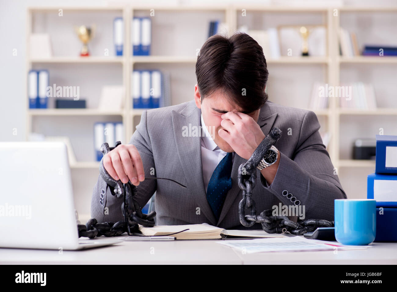 Businessman tied with chains to his work Stock Photo - Alamy