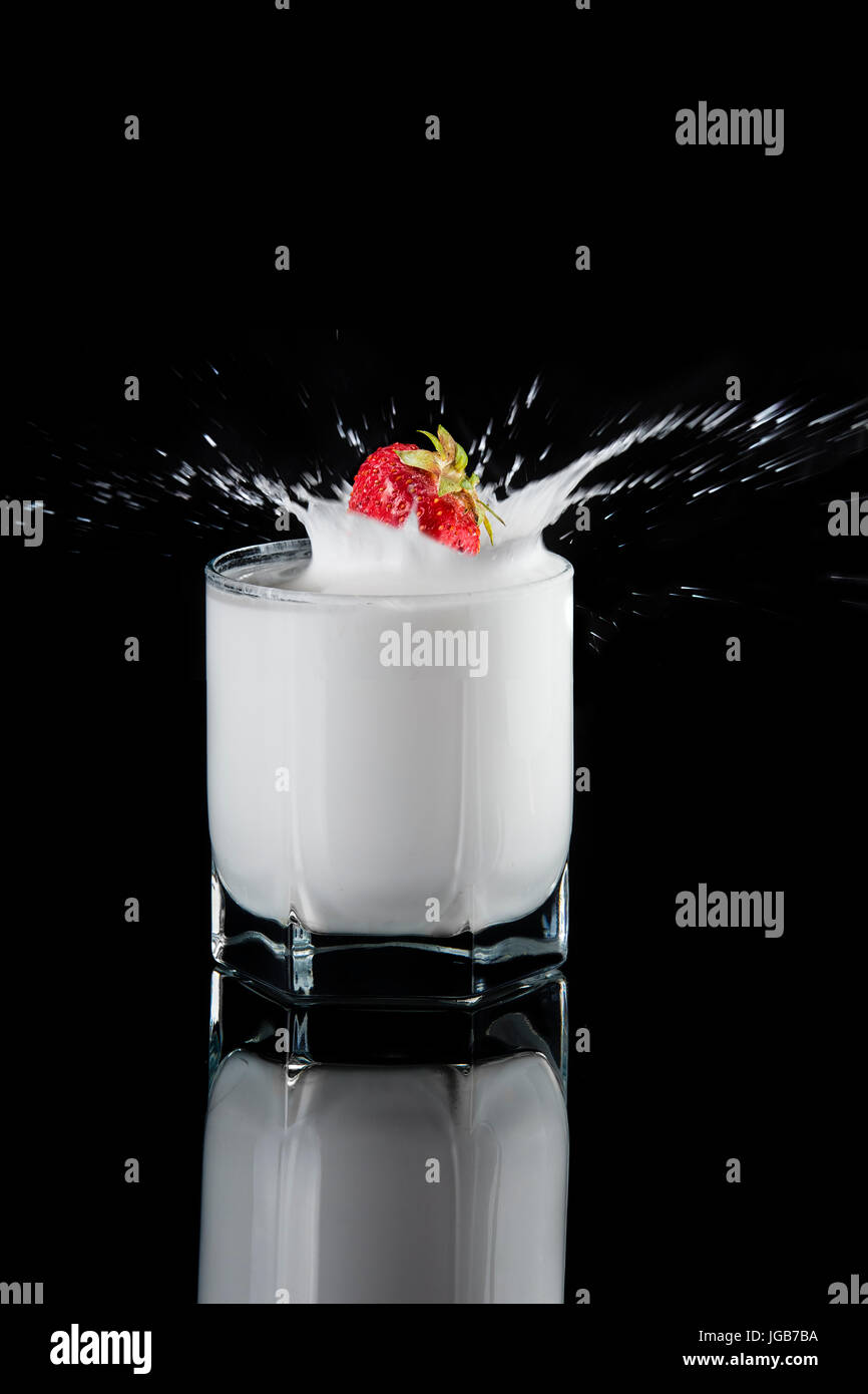 Strawberries fall into milk, splash, splashes on a black background ...