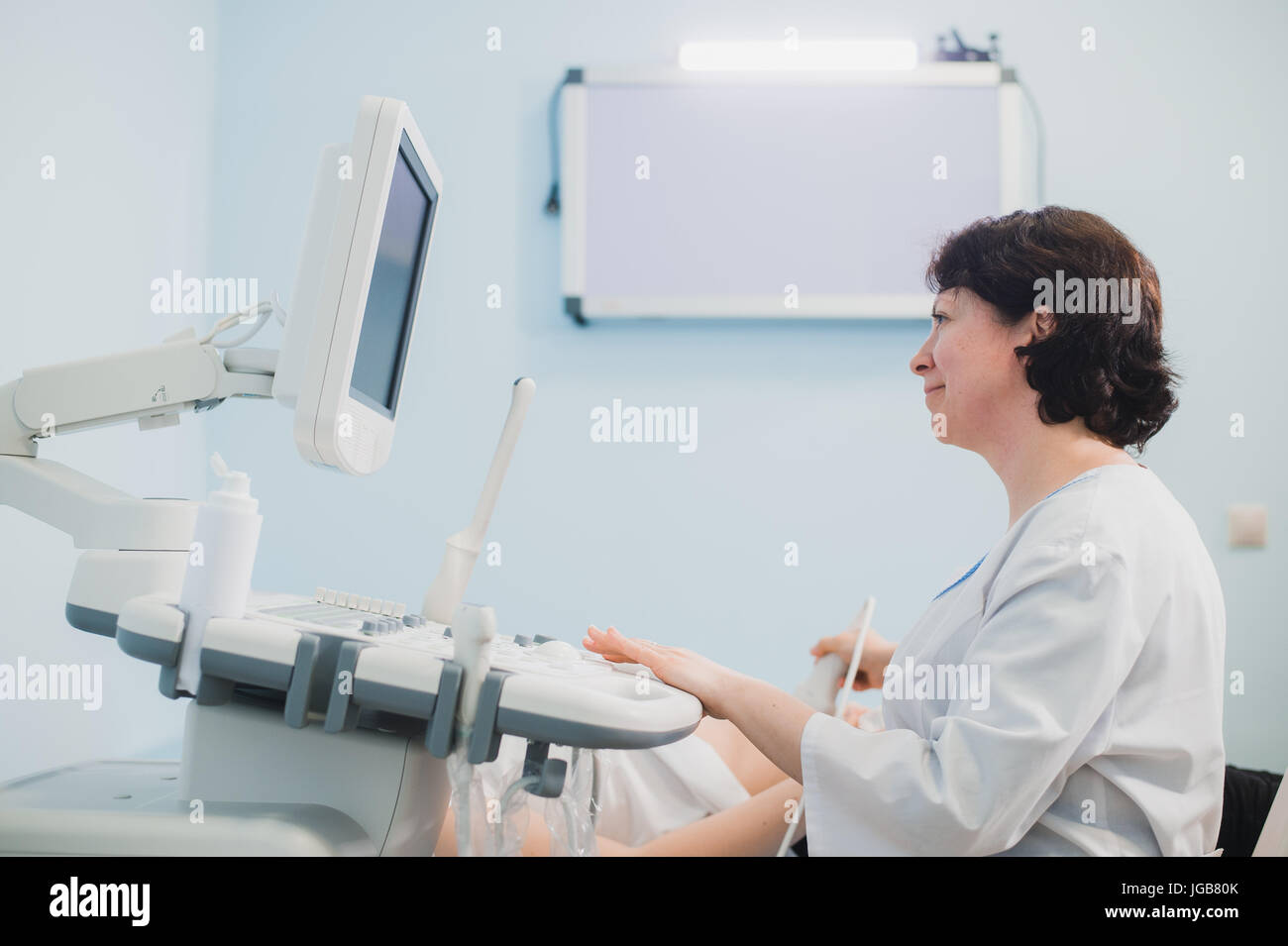 Doctor using ultrasound equipment screening hi-res stock photography ...