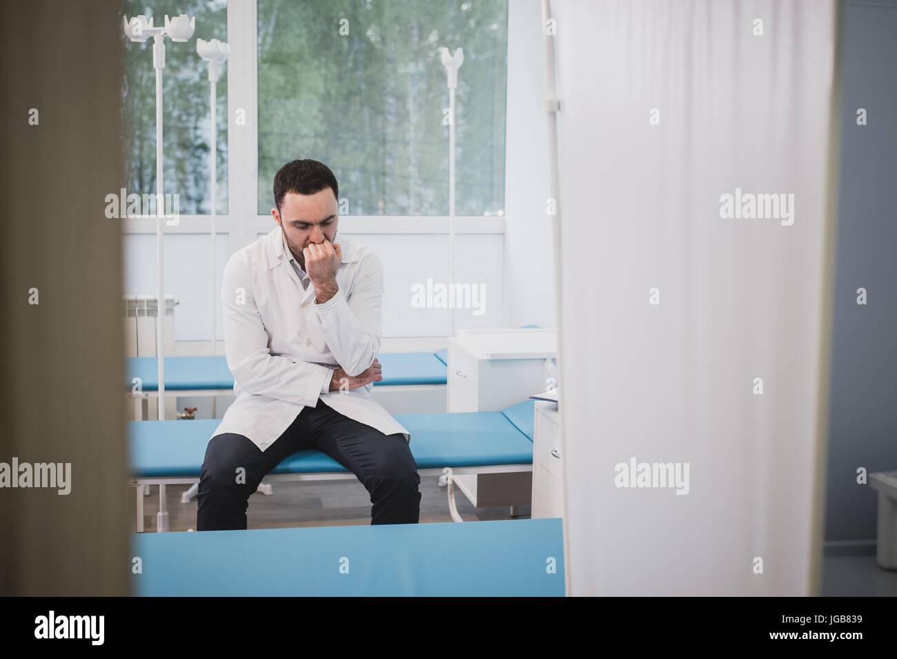 Tired doctor sitting alone in hospital ward Stock Photo - Alamy