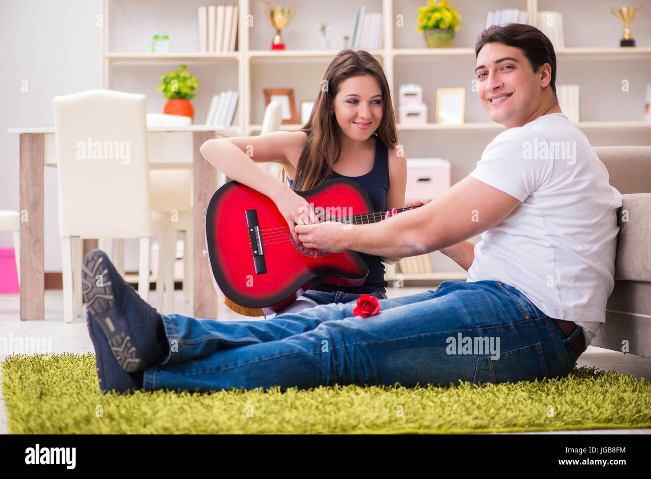 Romantic pair playing guitar on floor Stock Photo - Alamy