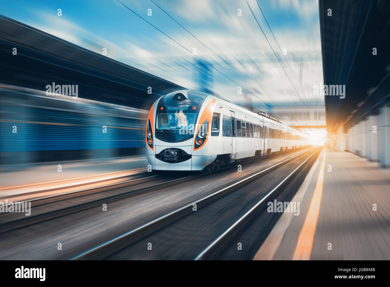 High speed train at the railway station at sunset in Europe. Modern intercity train on railway ...