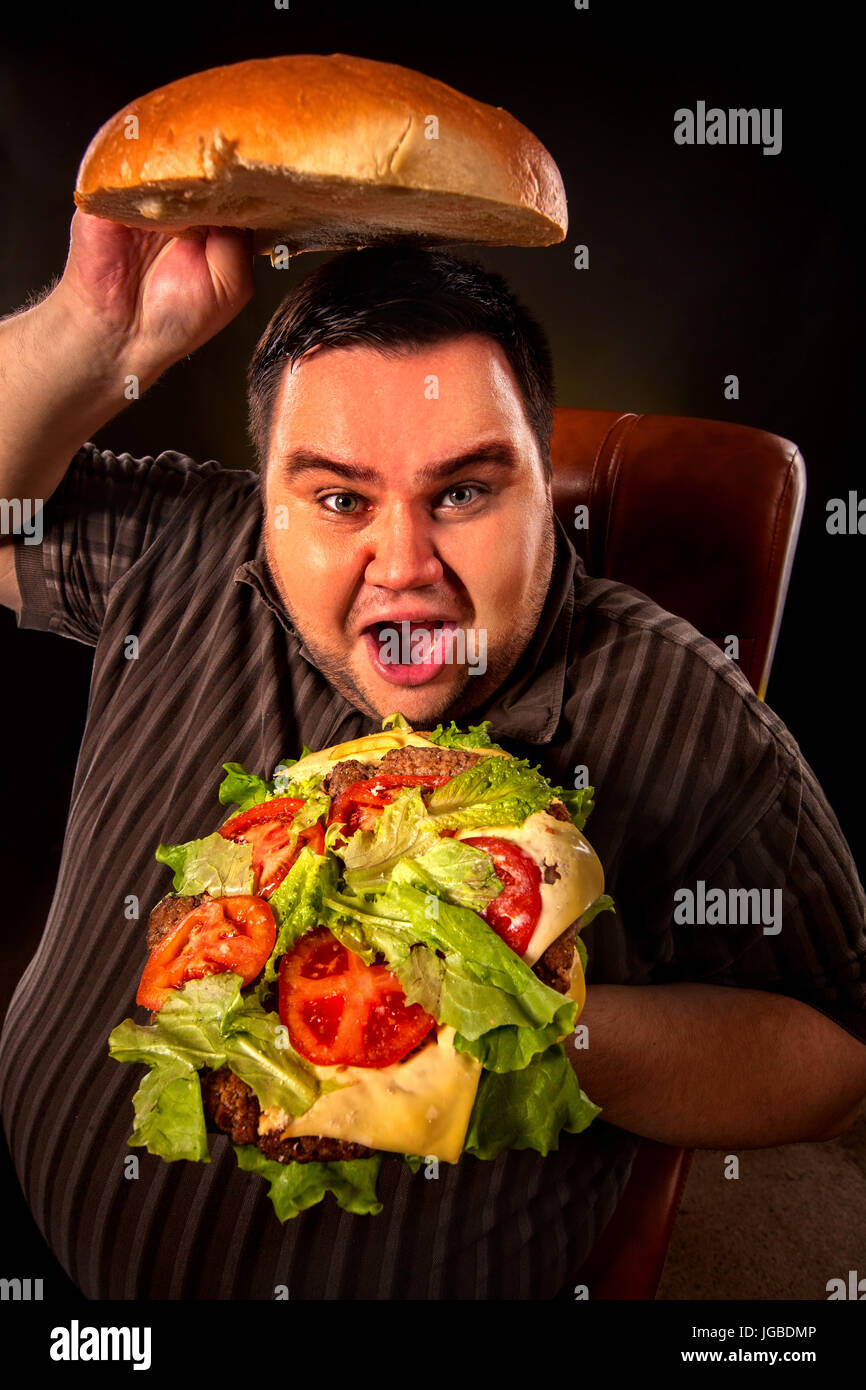 Fat man eating fast food hamberger. Breakfast for overweight person ...