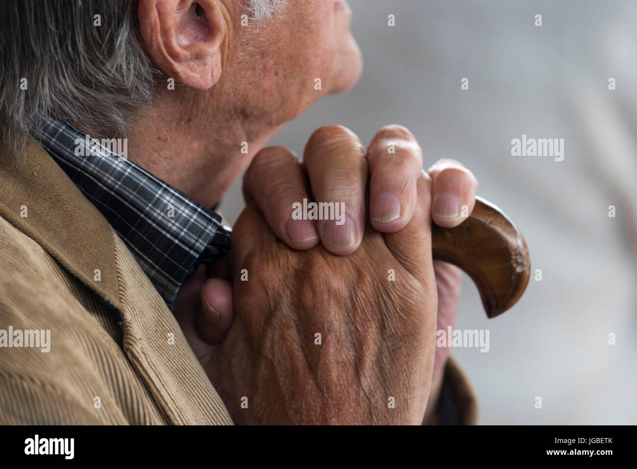 An OAP looks on with his hand on a walking stick Stock Photo - Alamy