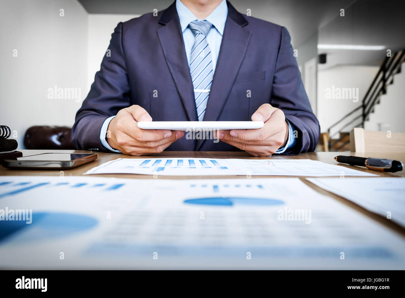 Multitasking. Handsome young man working with touchpad while sitting on ...