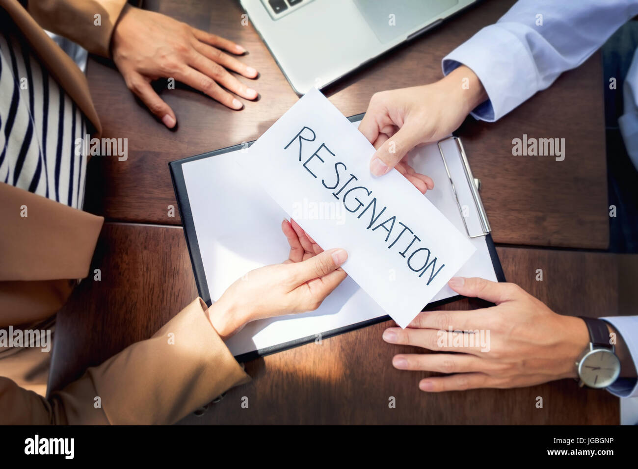 Hand of a businessman hands over a resignation letter on a wooden table ...