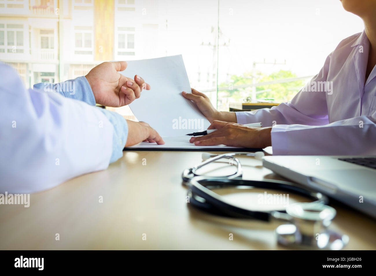 Two doctors discussing patient notes in an office pointing to a ...