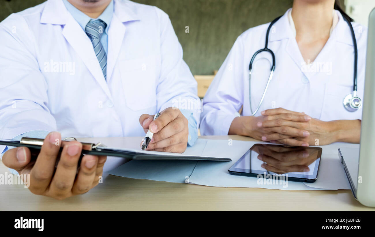 Two doctors discussing patient notes in an office pointing to a ...