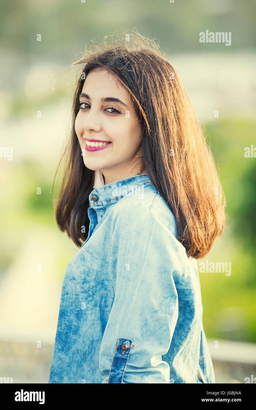 Beautiful young woman looking over shoulder smiling outdoors Stock ...