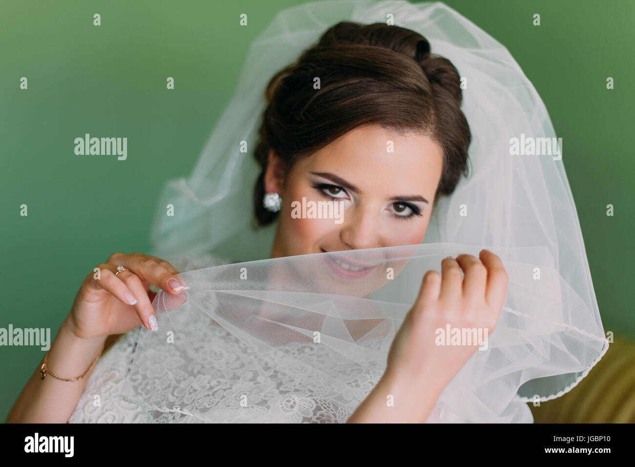Beautiful young shy bride hiding behind her veil Stock Photo - Alamy