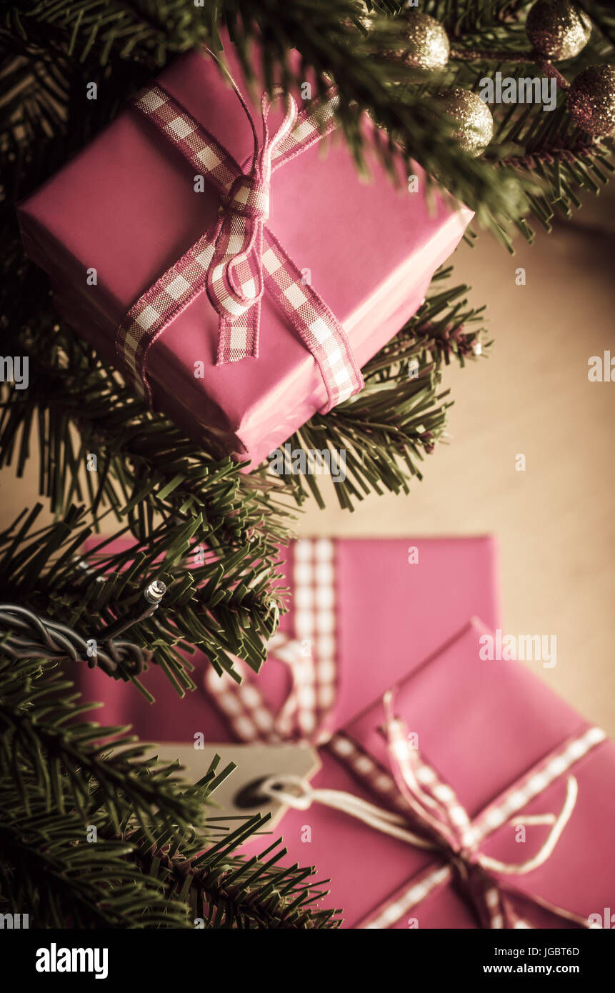 Pink Christmas gift boxes in branches and around base of decorated tree ...