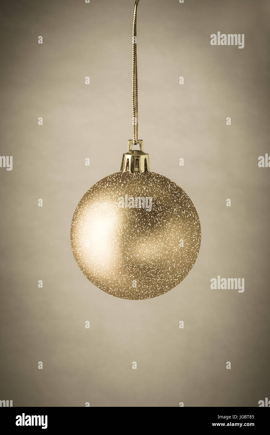 A single sparkling gold glitter Christmas bauble, hanging on gilt ...