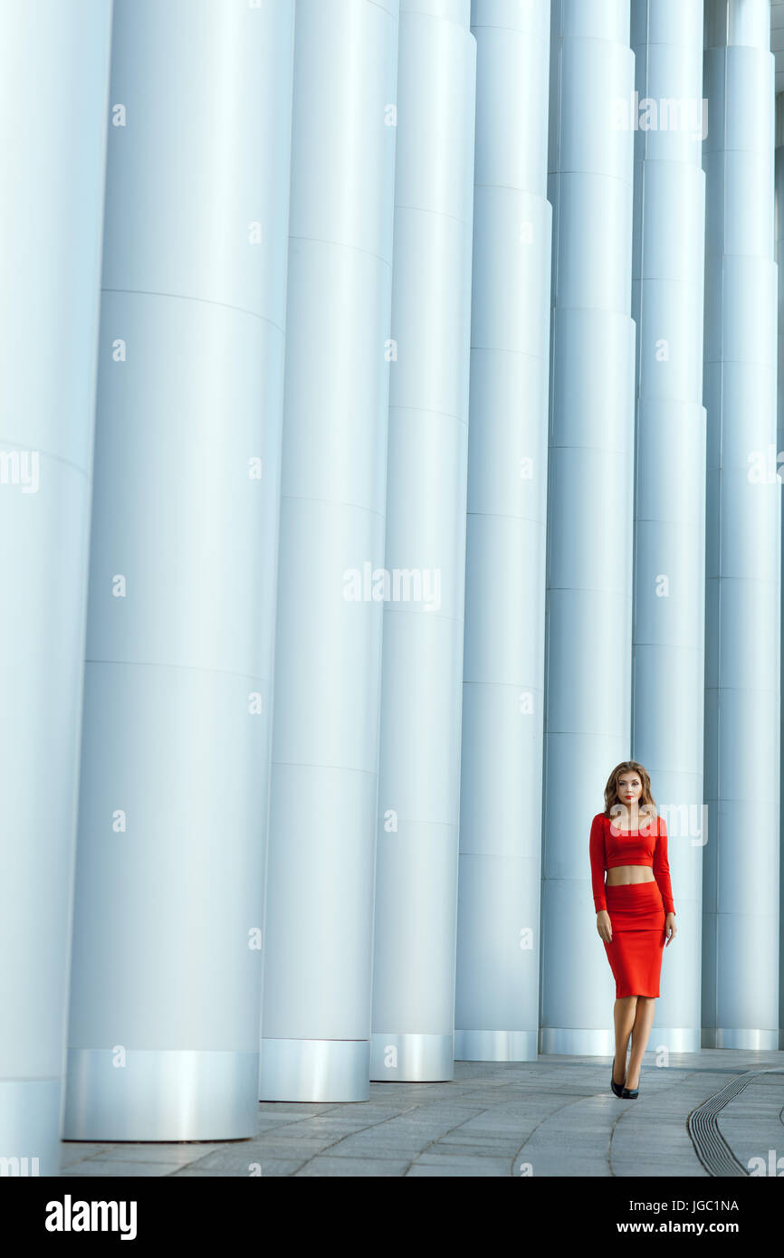Girl in the red suit comes by tall columns. Fashion photography Stock ...