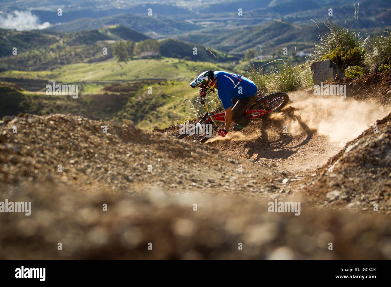 A downhill mountain bike rider slides his bicycle through a corner on a ...