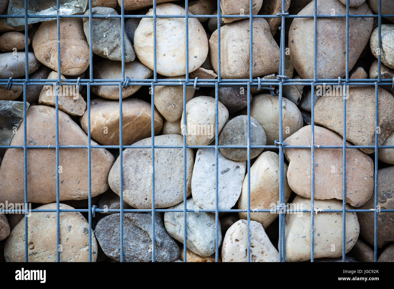 metallic basket net filled by natural stones as a fence Stock Photo - Alamy