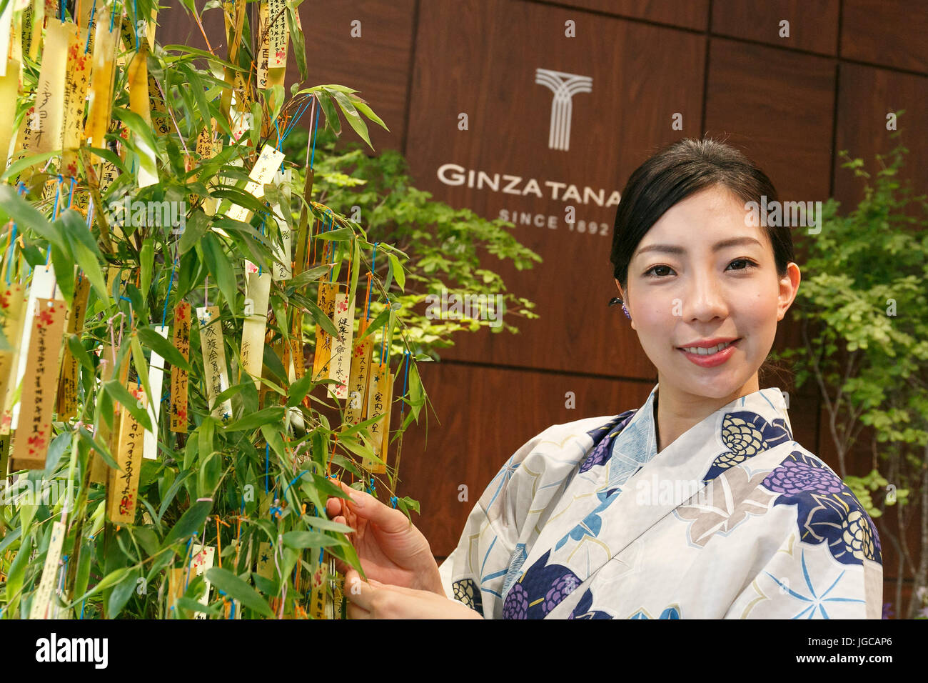 Store staff wearing traditional Japanese kimono poses next to a bamboo ...