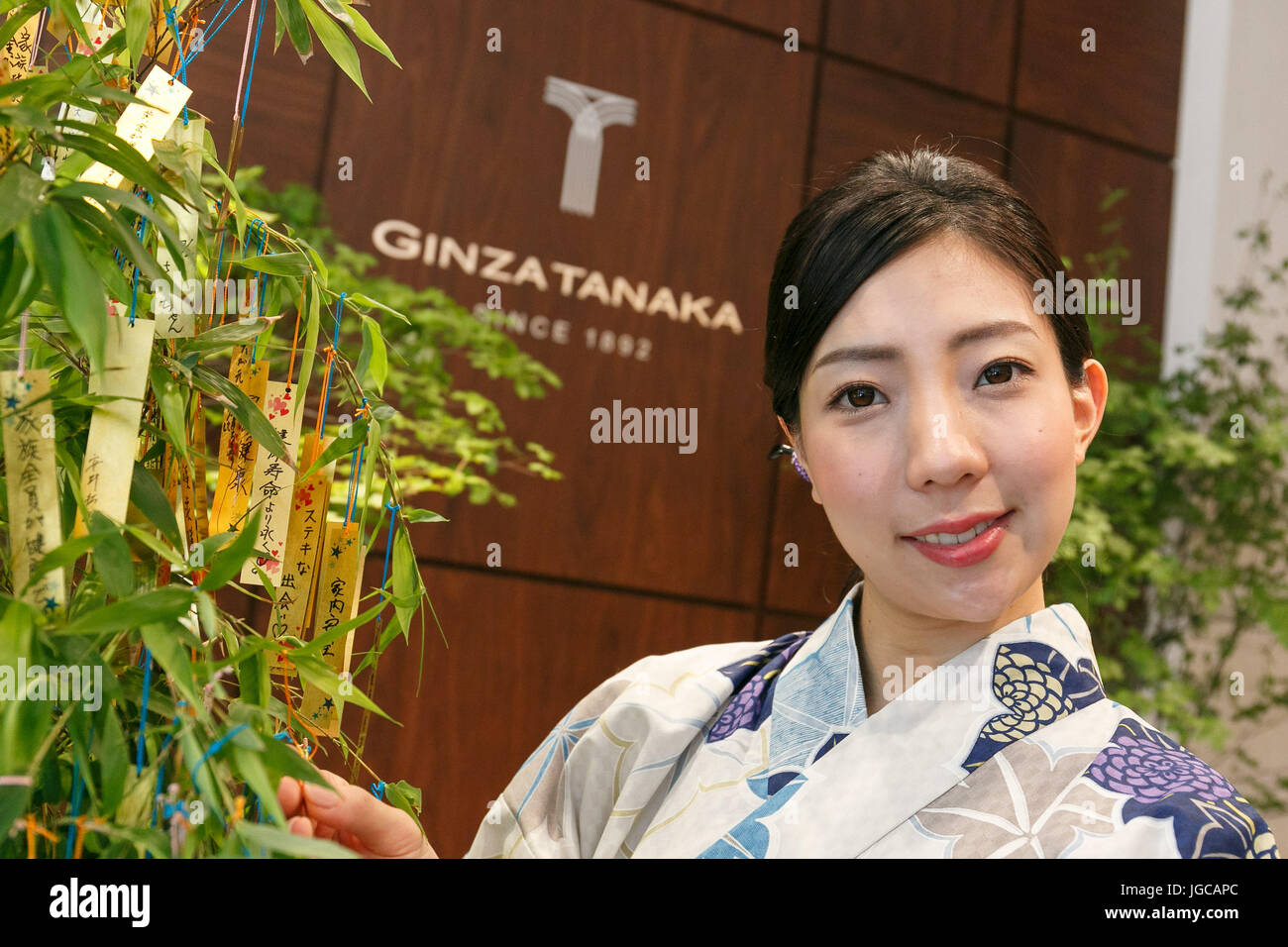 Store staff wearing traditional Japanese kimono poses next to a bamboo ...