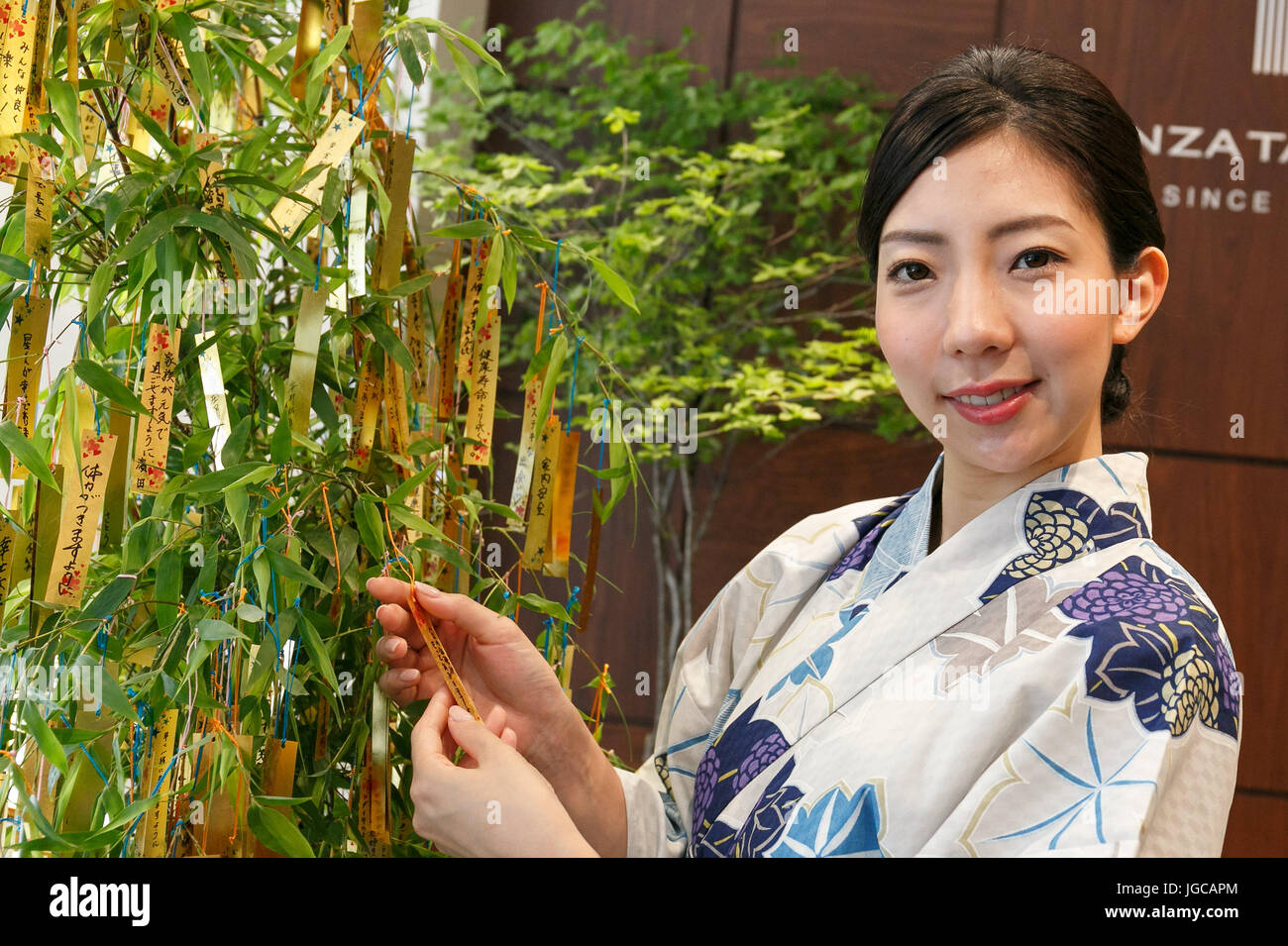 Store staff wearing traditional Japanese kimono poses next to a bamboo ...