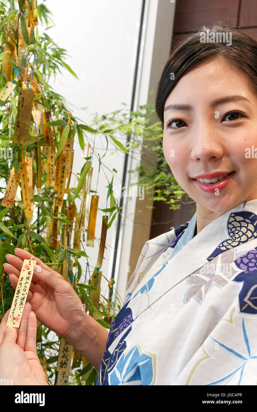 Store staff wearing traditional Japanese kimono poses next to a bamboo ...