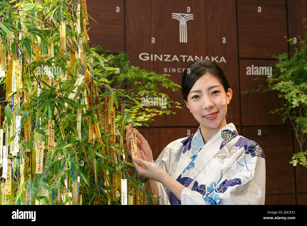 Store staff wearing traditional Japanese kimono poses next to a bamboo ...