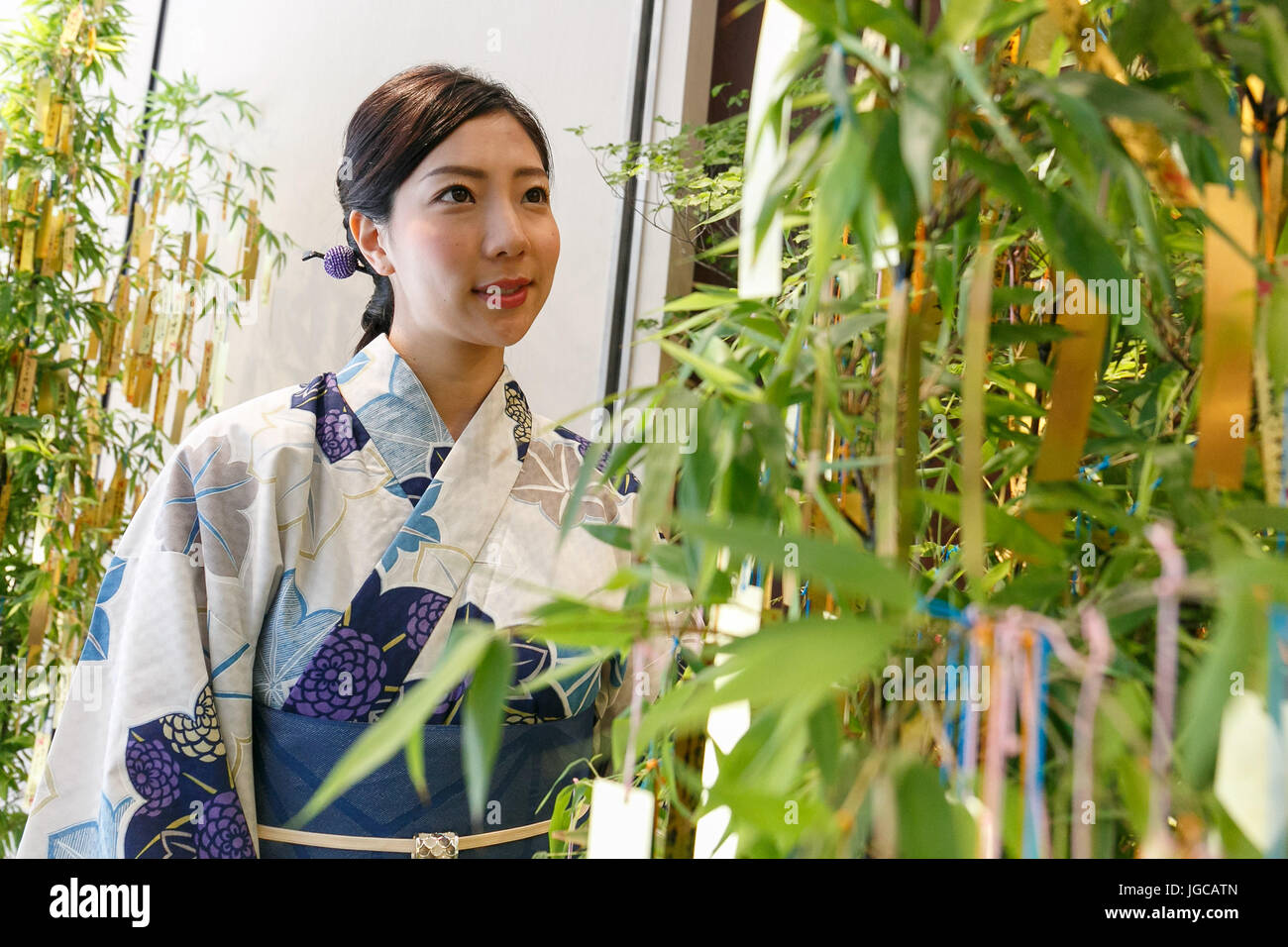 Store staff wearing traditional Japanese kimono poses next to a bamboo ...