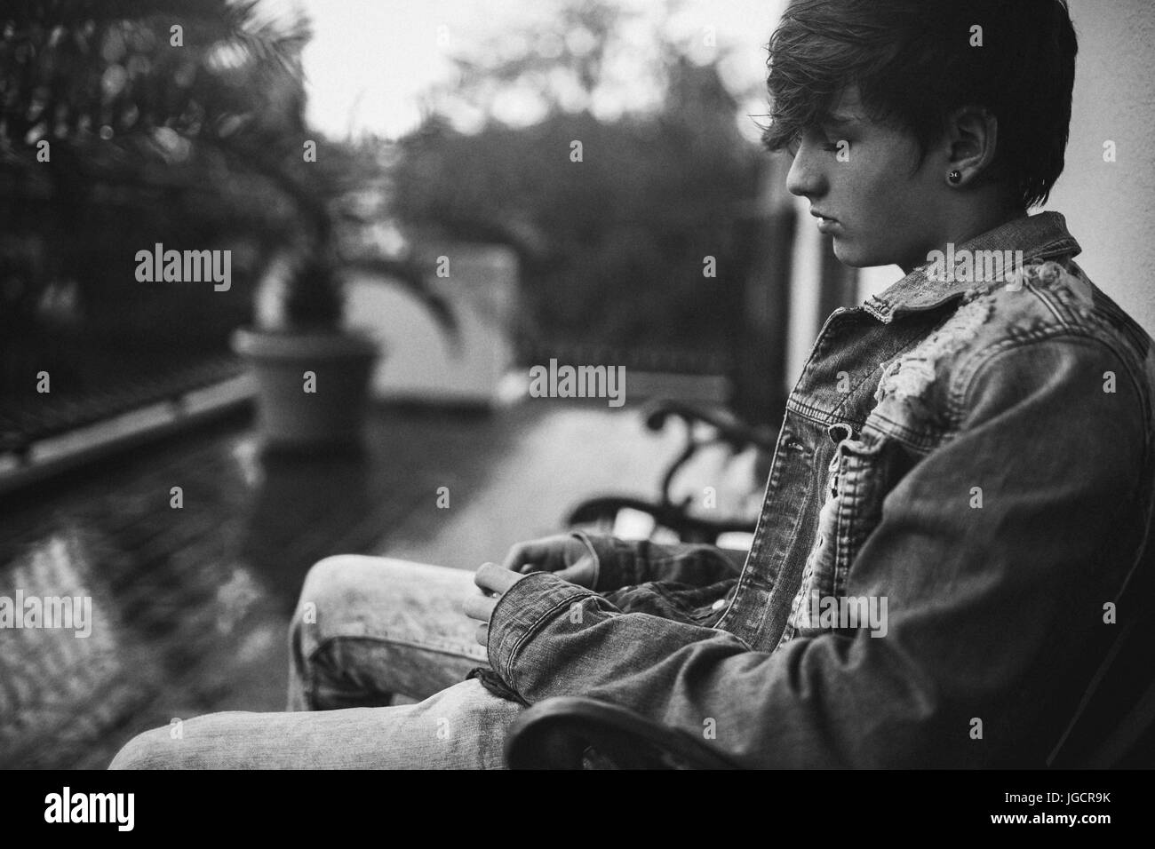 Teenage boy sitting on a bench Stock Photo - Alamy
