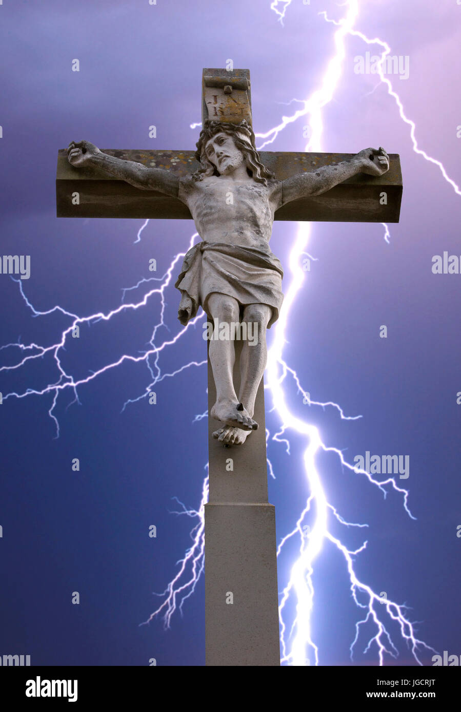 stone cross with Jesus in front of sky with lightning Stock Photo - Alamy