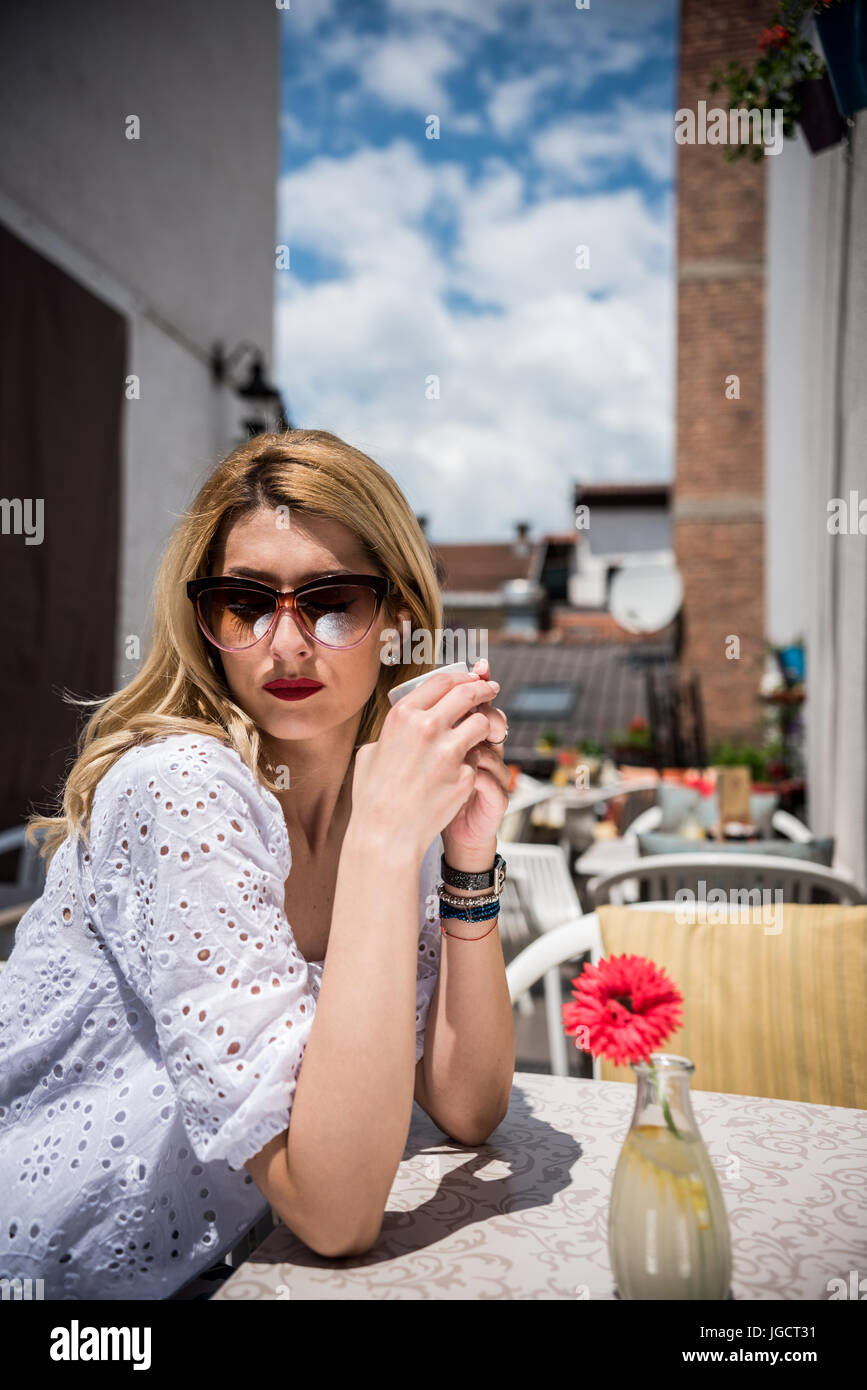 Woman enjoying a cup of coffee at a cafe outdoors Stock Photo - Alamy