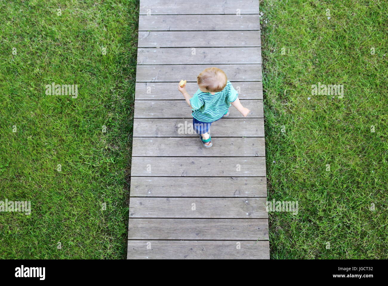 Overhead view of a boy walking along a wooden boardwalk Stock Photo - Alamy