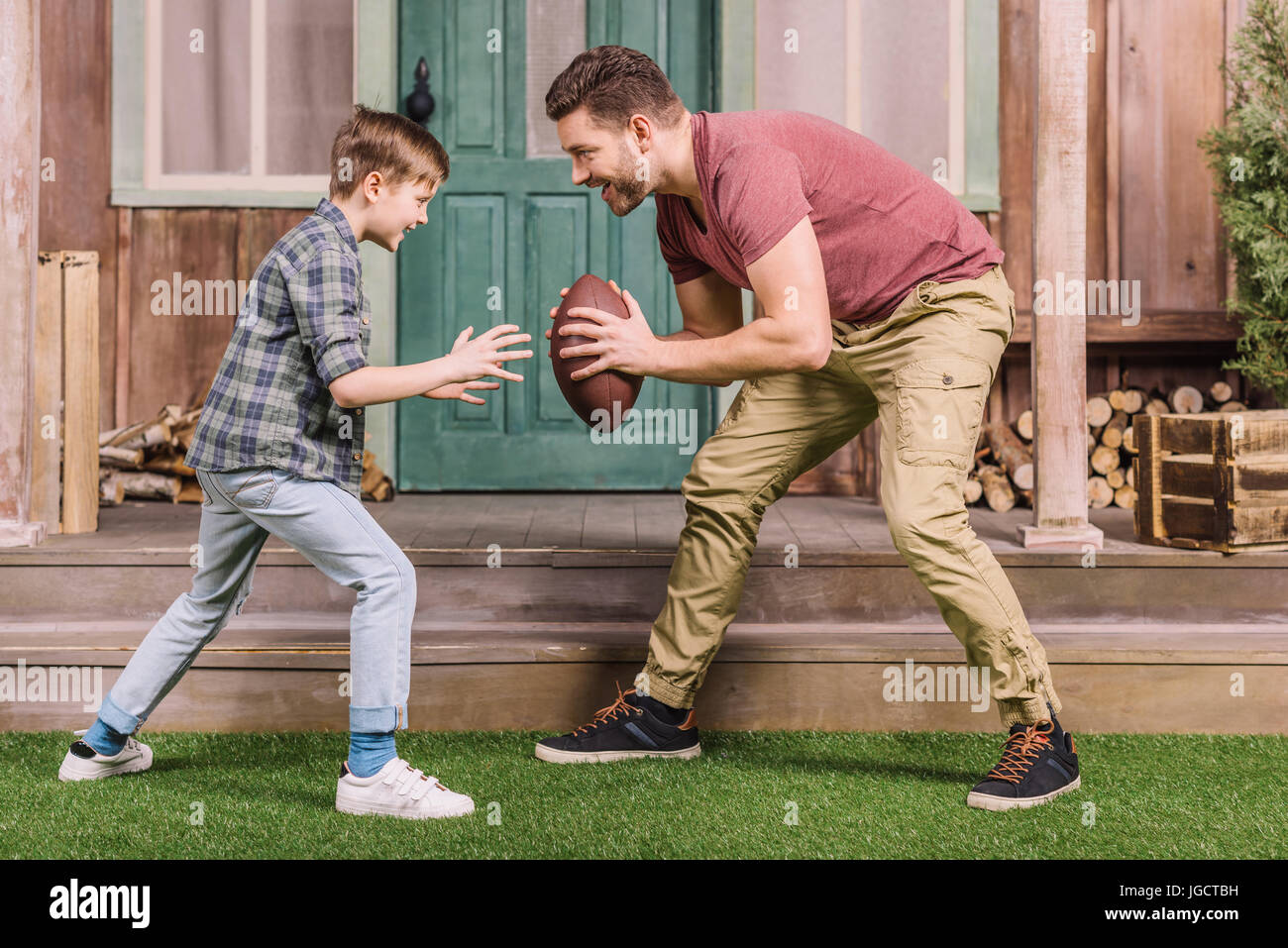 father with little son playing american football with ball at backyard ...