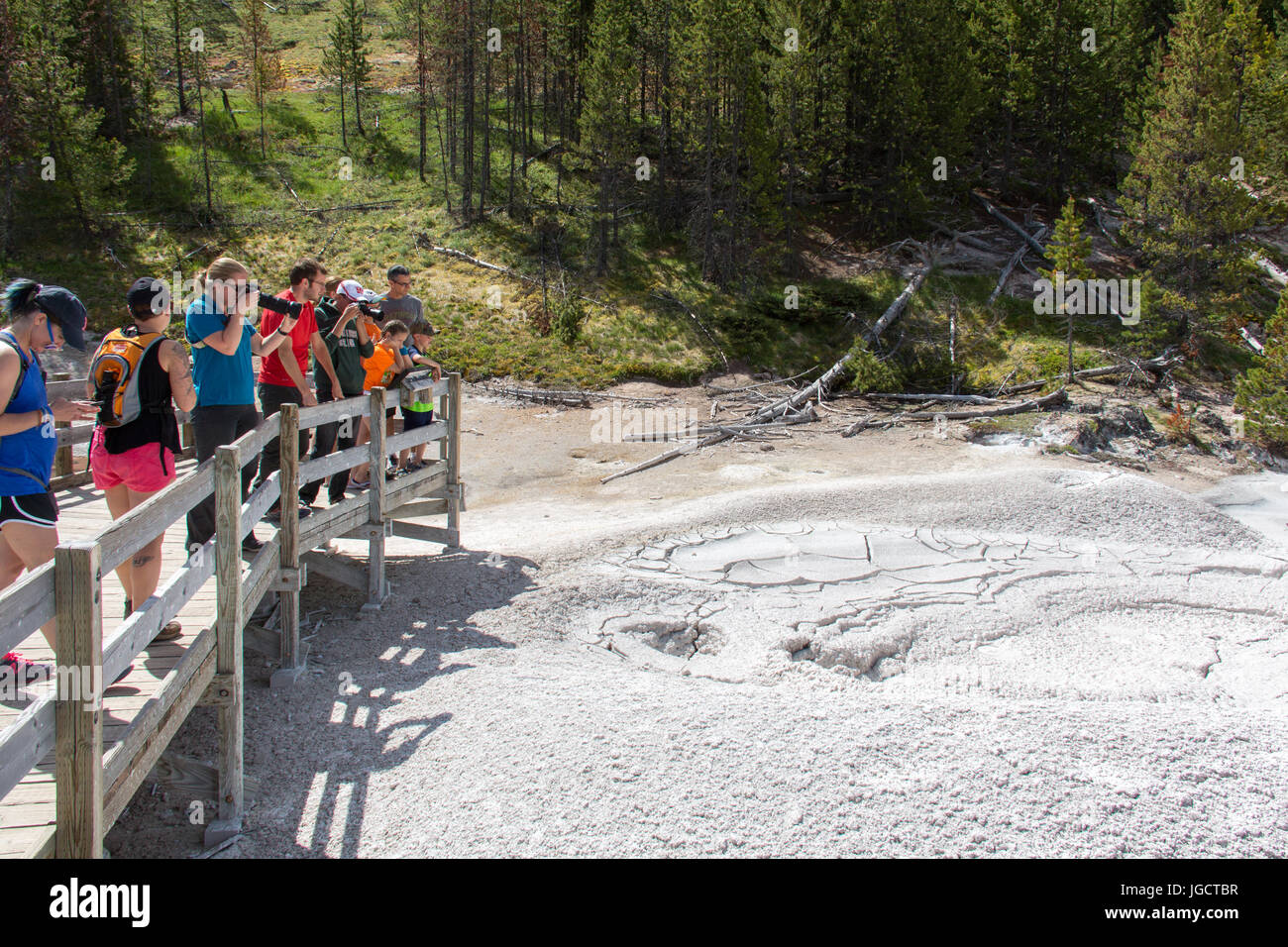 Tourists are taking pictures of a geyser from the boardwalk at Artists ...