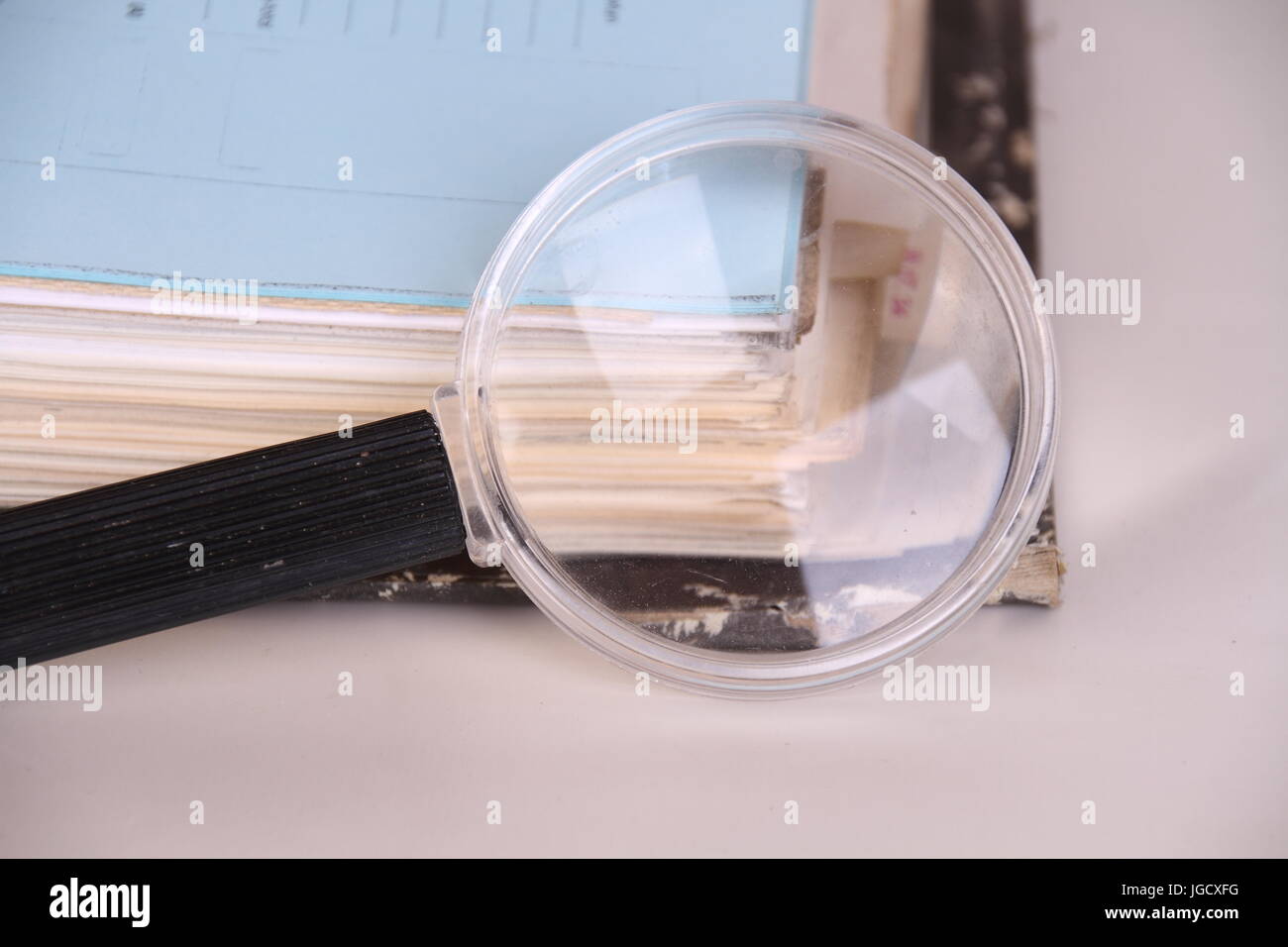 A paper file with documents and a magnifying glass on a white ...